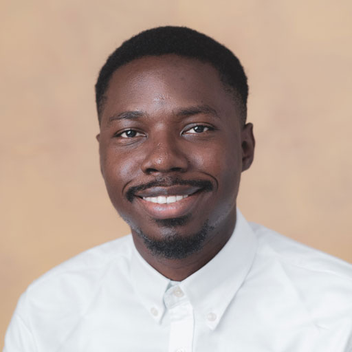 Femi smiling in a portrait photograph.